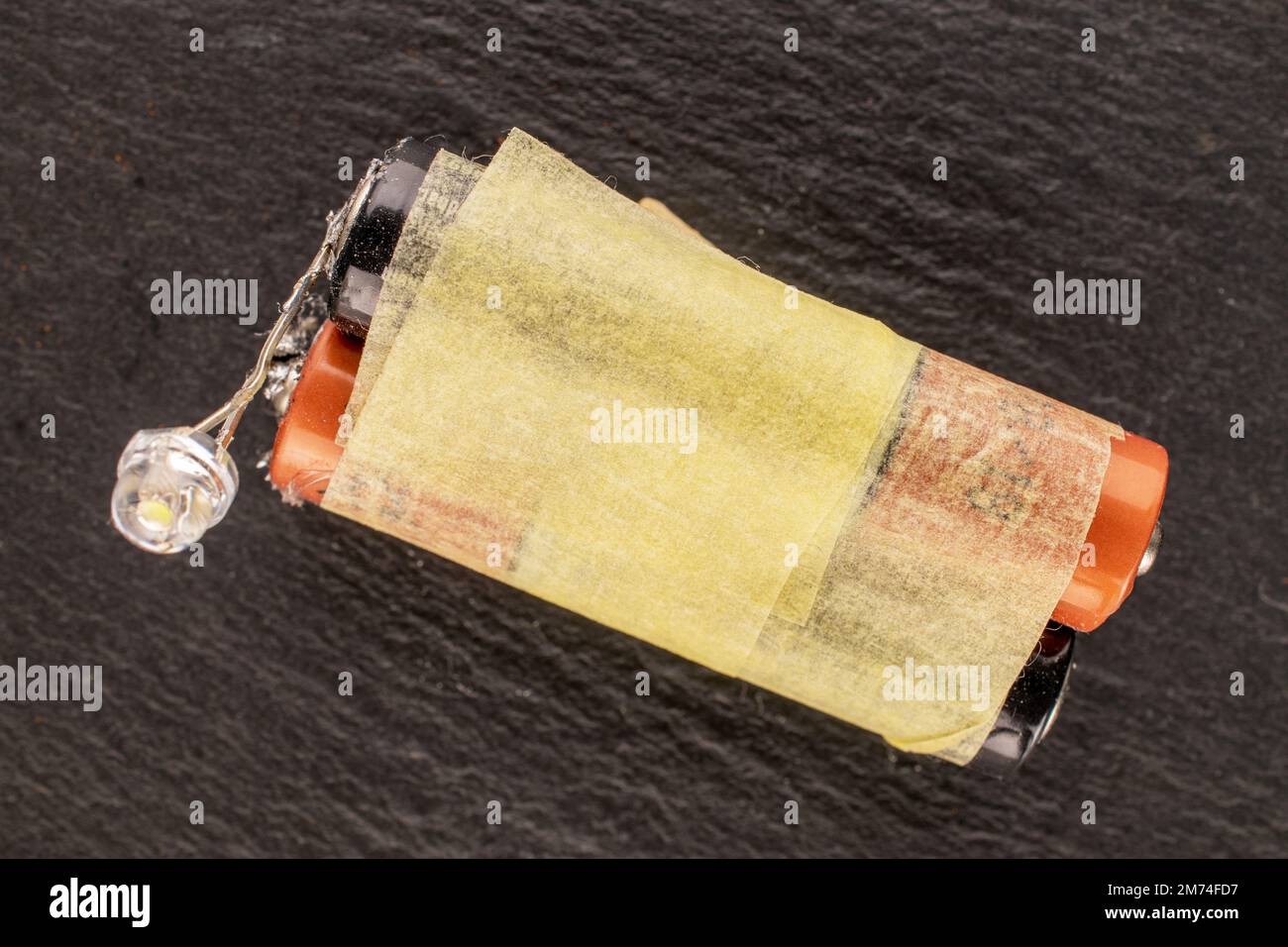 A flashlight with two batteries and a diode on a shale stone, top view ...
