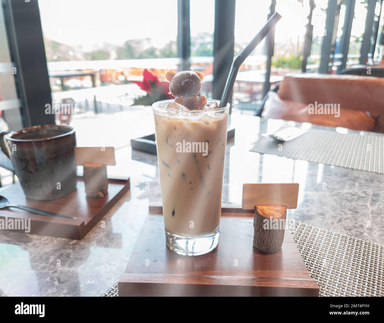 Glass of latte coffee top and a bear syrup ice on wooden plate with ...