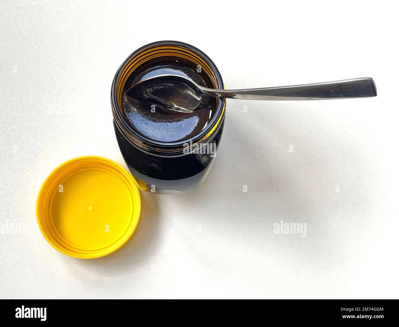 A top closeup of a newly opened yeast extract marmite jar with a spoon ...