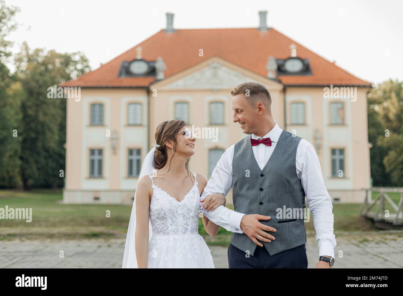 Charming, blissful married couple smiling and hold hands against new ...