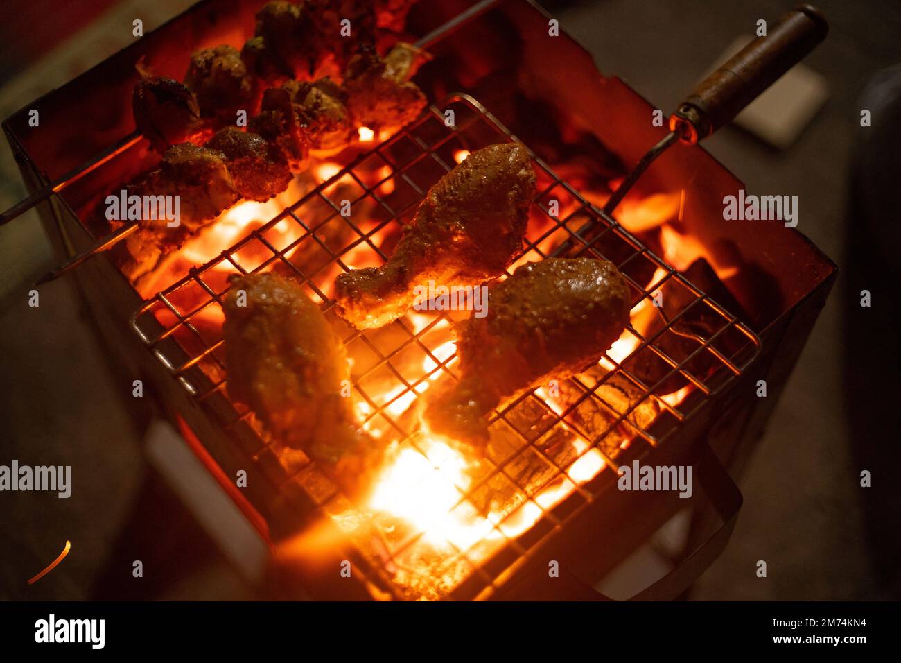 Meat and chicken with veg being roasted over a barbeque wood and coal ...