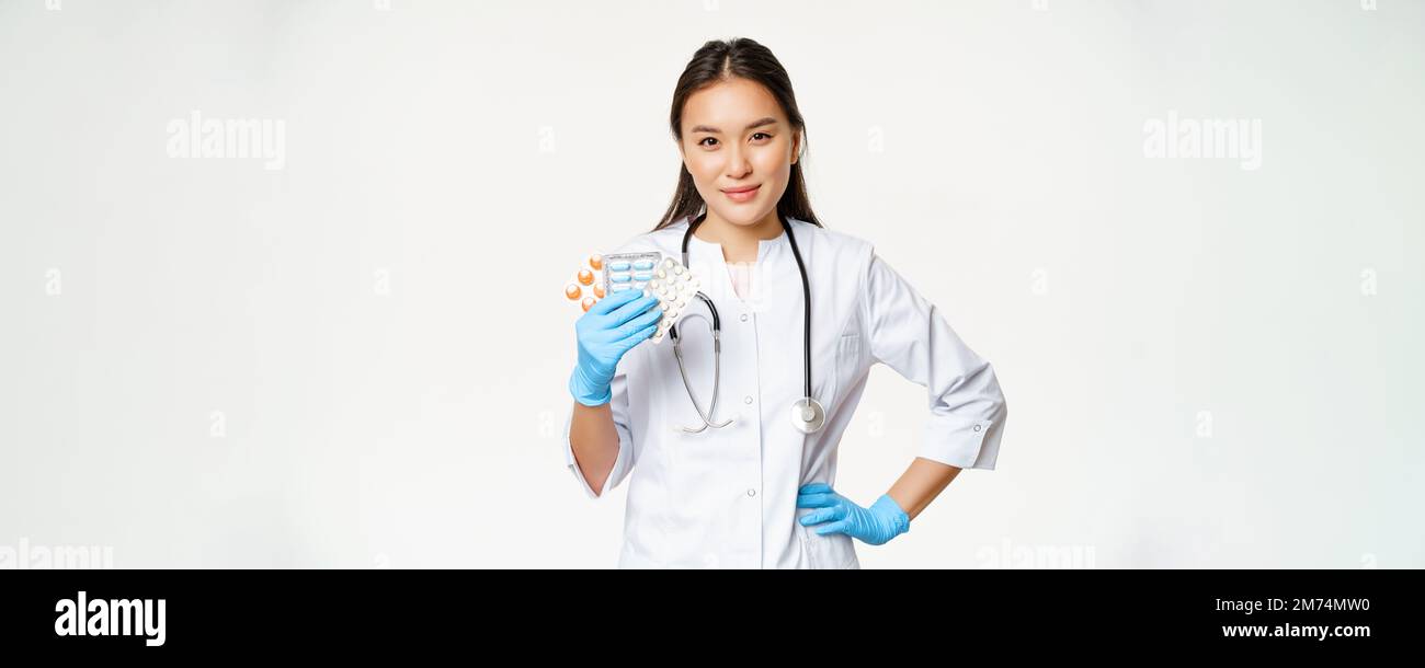 Asian female physician showing pills, medication, holding vitamins and ...