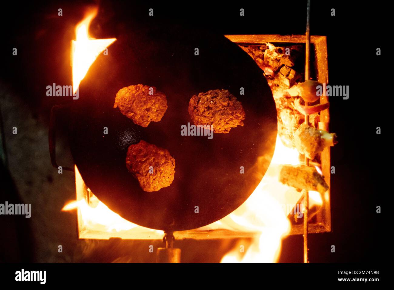 Top down shot meat patties being cooked on coal wood fire street food ...