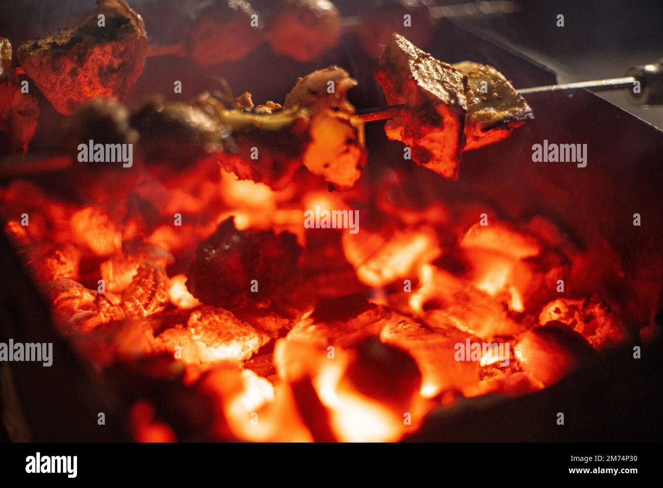 Meat and chicken with veg being roasted over a barbeque wood and coal ...