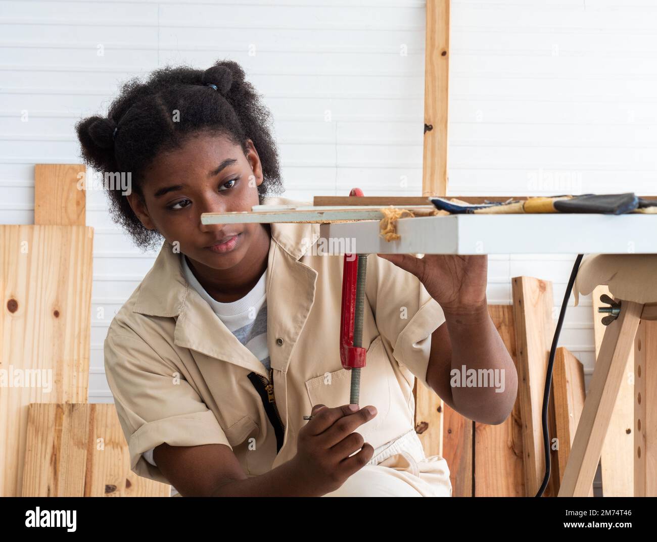 Concentrated young girl carpenter a clamp and choosing wood in the ...
