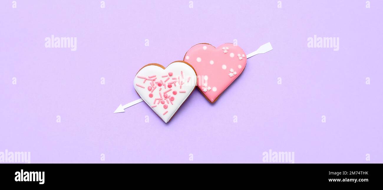 Composition with tasty heart shaped cookies and paper arrow on lilac ...