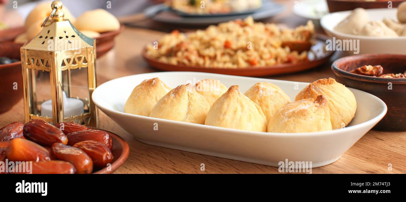 Traditional Arabic cookies with dates and fanoos lamp on table ...