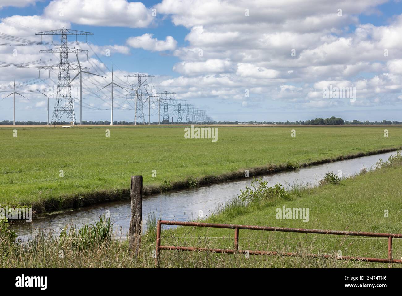 Dutch countryside in Groningen with wind turbines and power pylons ...