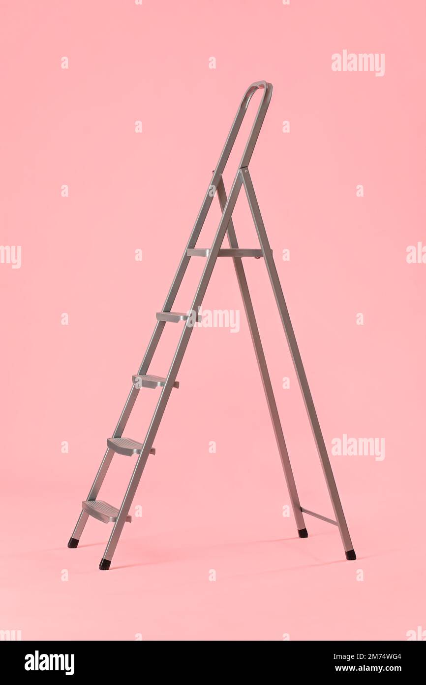 Maintenance ladder on pink background Stock Photo - Alamy