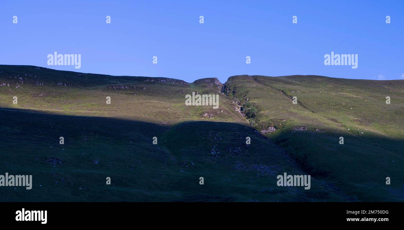 Sunlight on a ridge opposite the Grey Mare's Tail waterfall in southern ...