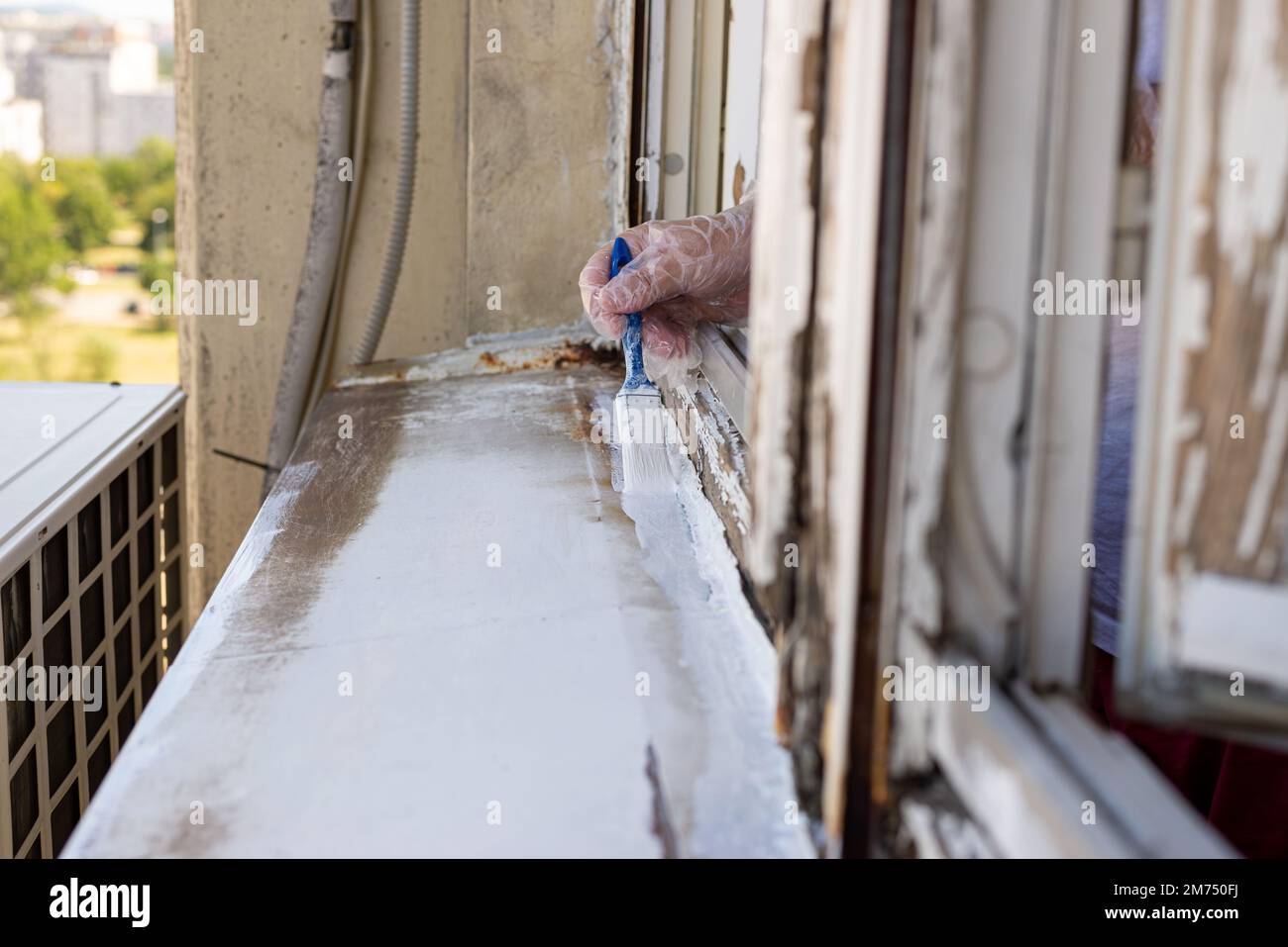 Hand holding a brush while painting an old window cill in white Stock ...