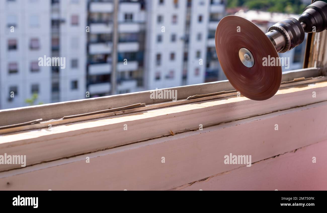 Sanding an old window frame during renovation work with an apartment ...