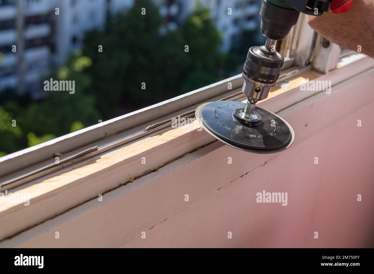 Sanding an old window frame during renovation work with an apartment ...