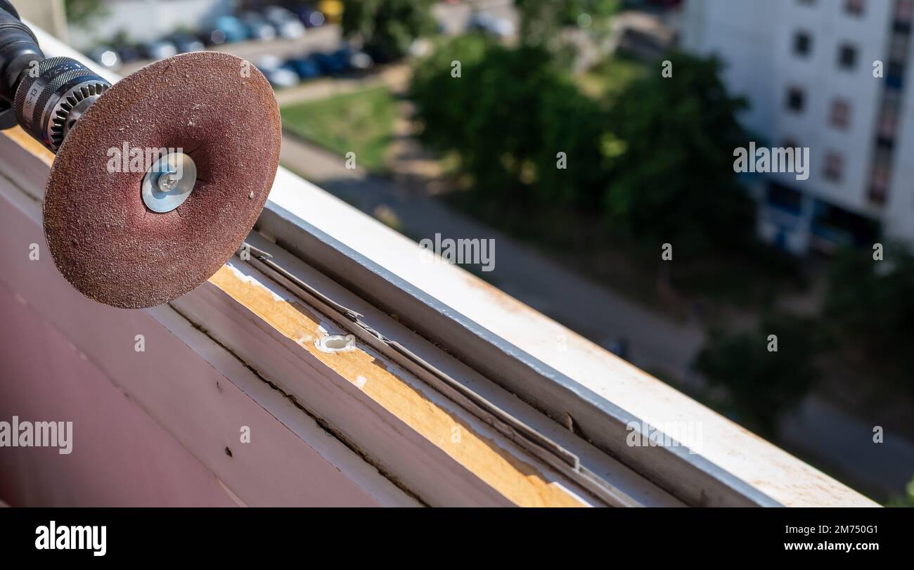 Sanding an old window frame during renovation work with a park of a ...