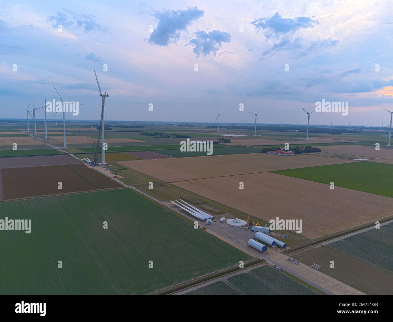Crawler crane is constructing a new wind turbine. Parts for another one ...