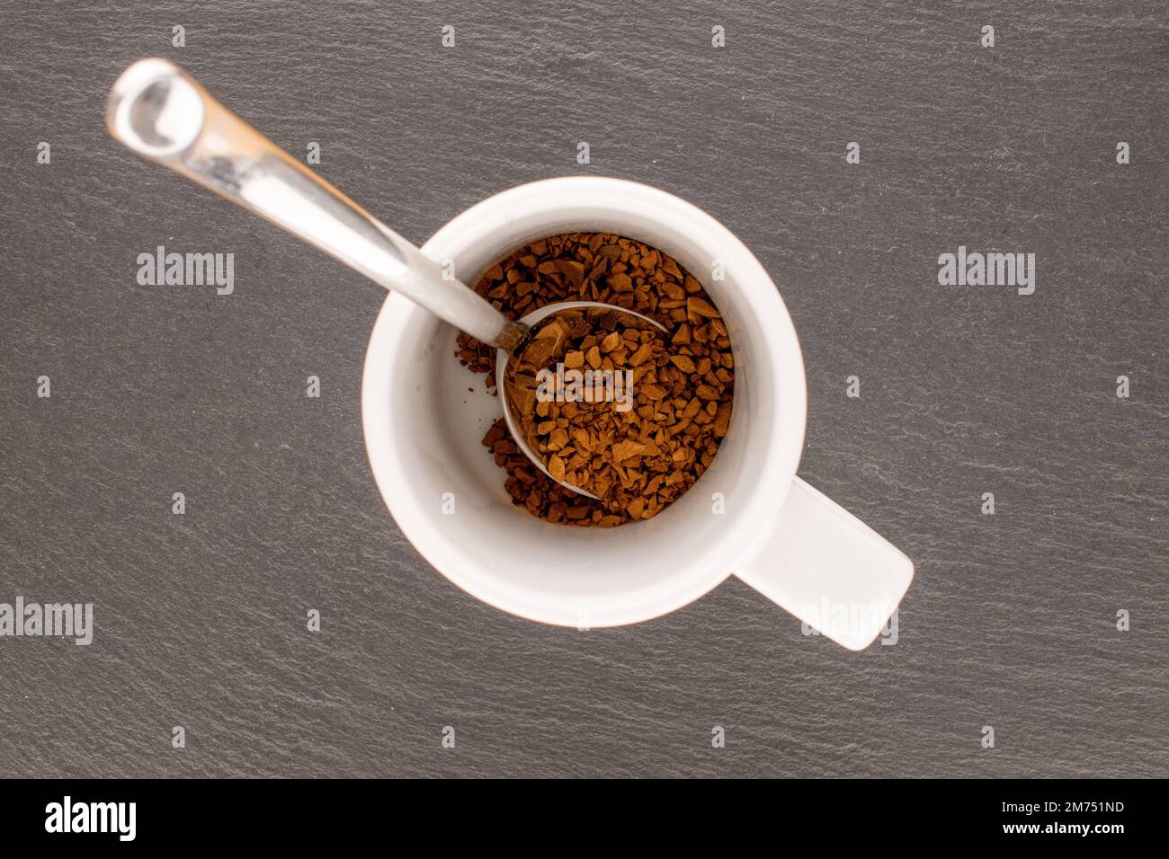 Fragrant instant coffee in white cup with metal spoon on slate stone ...