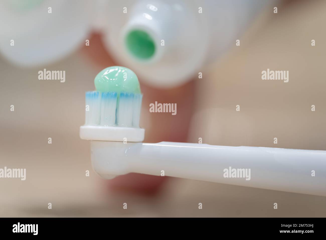 Tube of toothpaste pouring paste on an electric toothbrush, macro ...