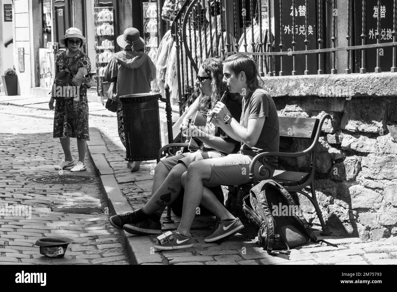 Buskers, street performers playing music, seated on a bench in Cesky ...