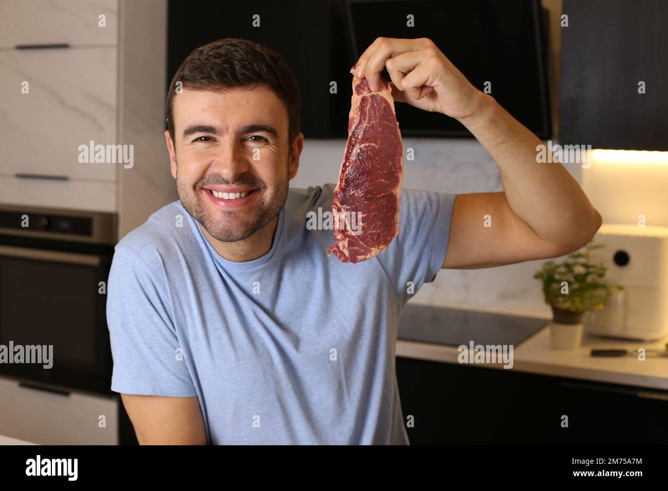 Meat lover showing a delicious raw steak Stock Photo - Alamy