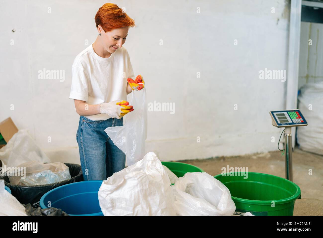 Enthusiastic female volunteer worker in latex gloves sorting diverse ...