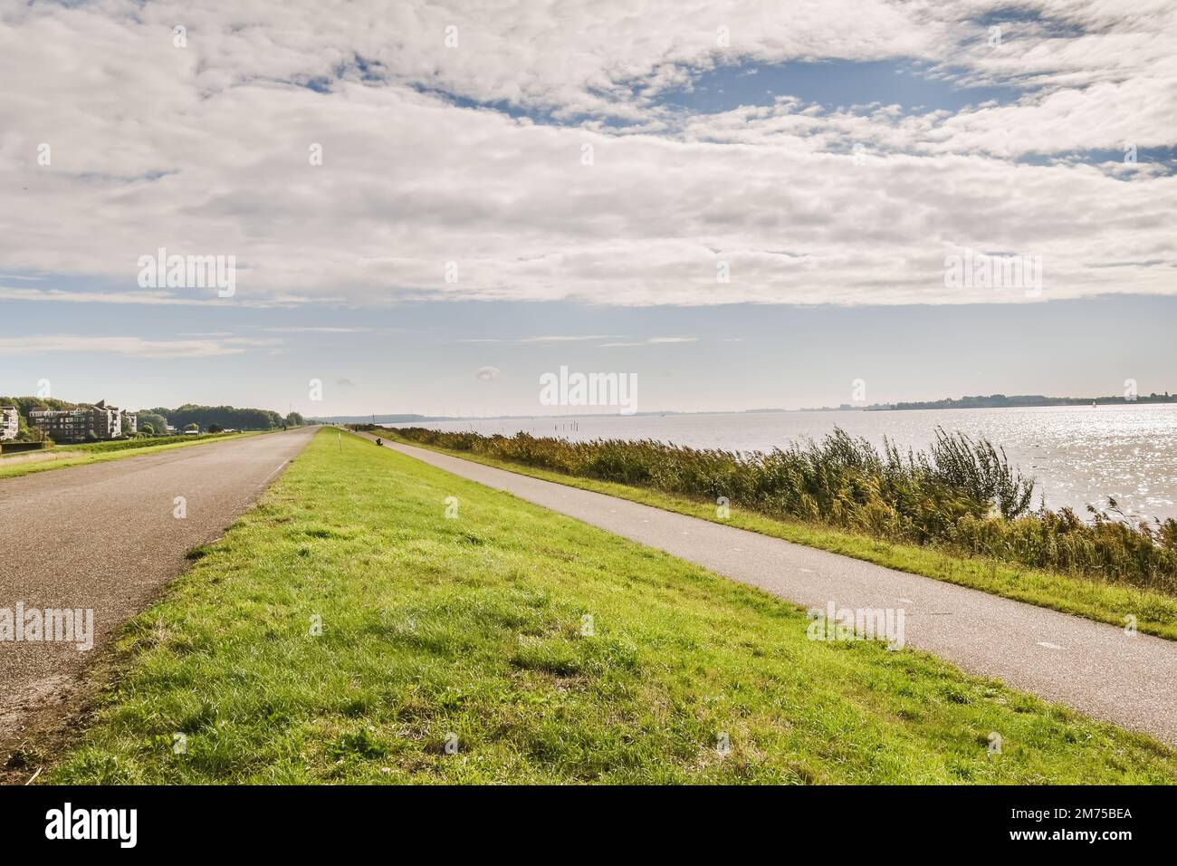 a road next to the water and some buildings in the distance with blue ...