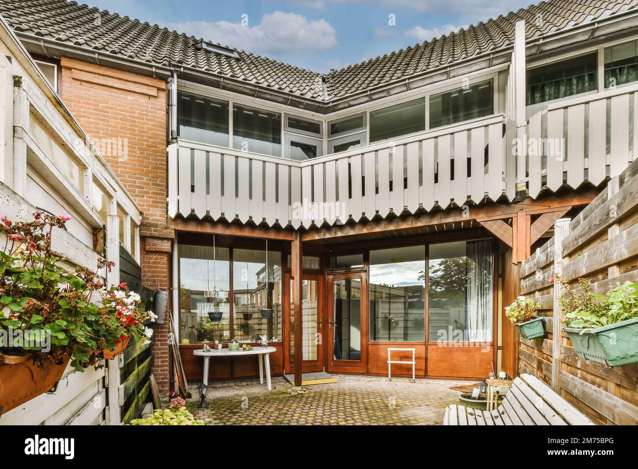 an outside area with a bench and potted plants on the ground in front ...