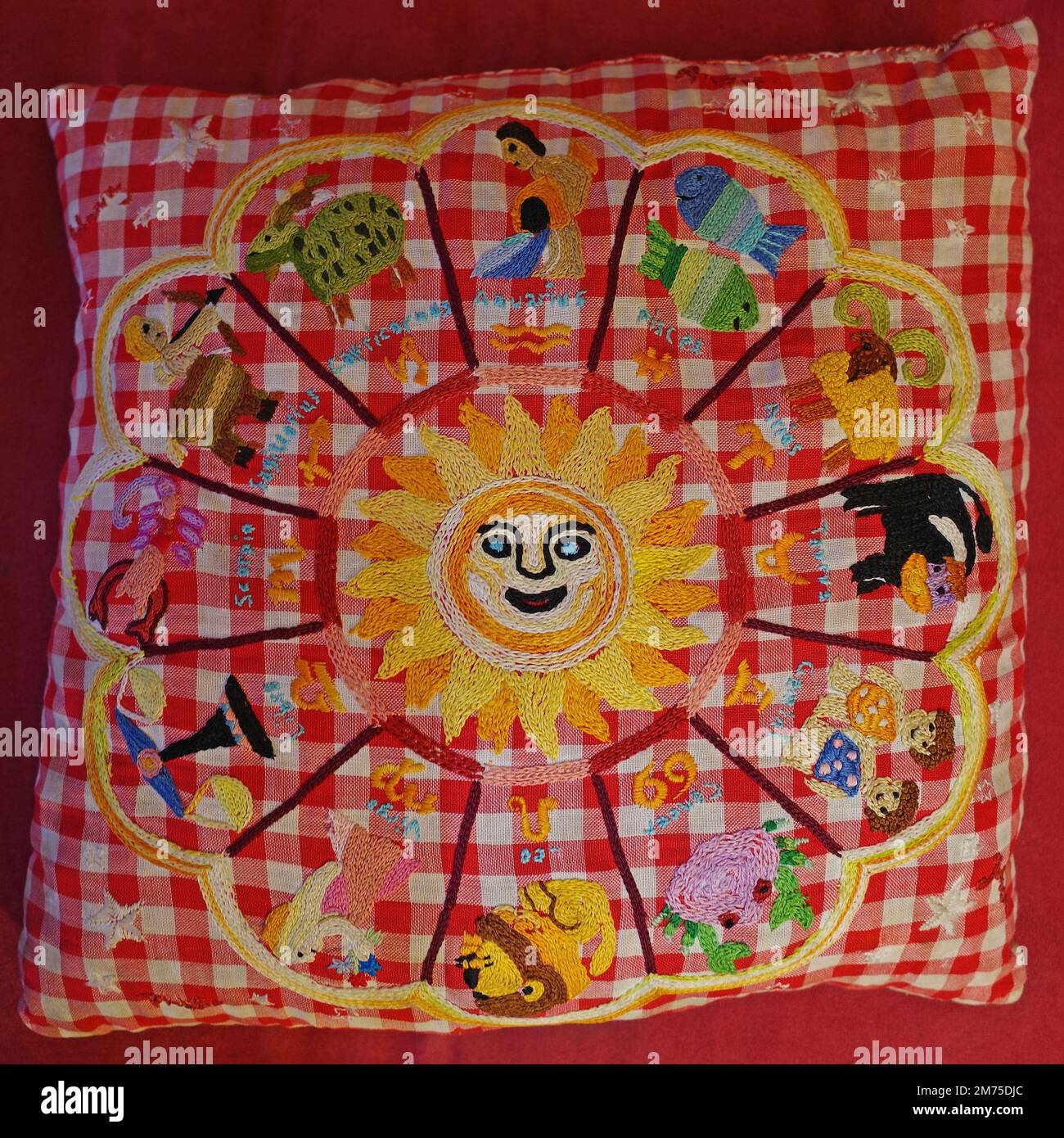 A red and white checkered cushion with embroidered astrological signs ...