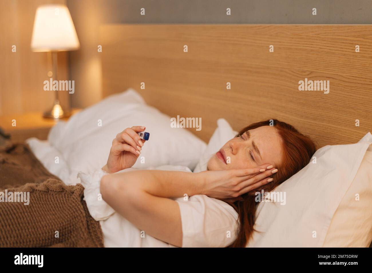 Sick tired woman touching head temple after using thermometer to ...