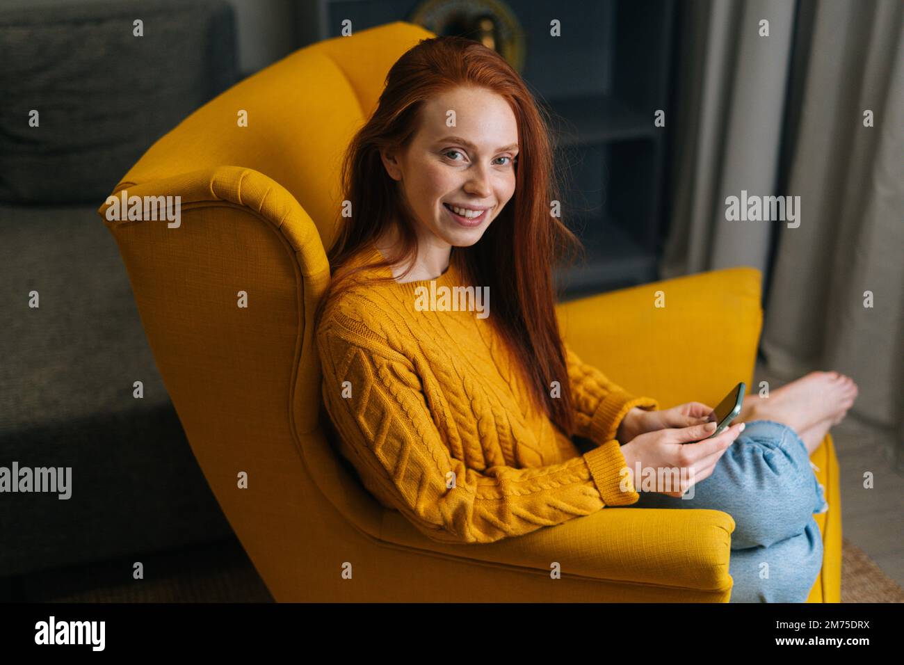 High-angle view of positive young woman using smartphone sitting in ...