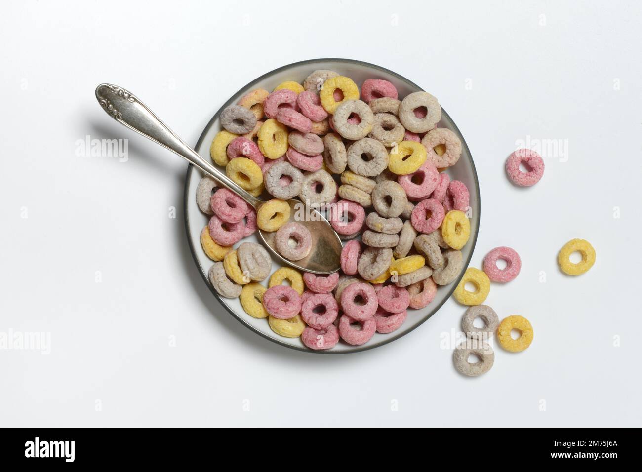 Fruit-flavoured cereal rings in bowl and spoon, children's breakfast ...