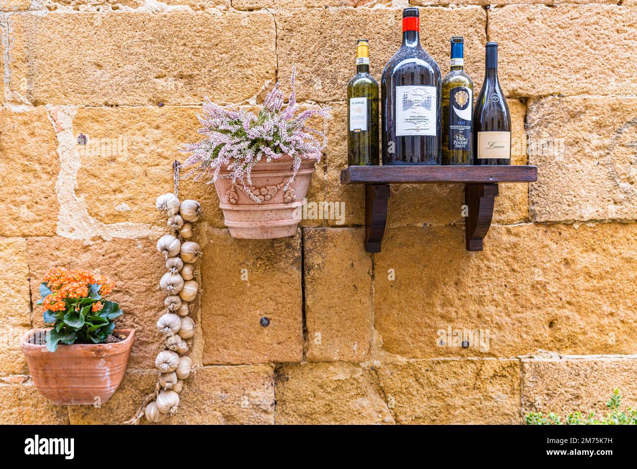 Wine bottles, flower box and garlic as decoration on a house wall in ...