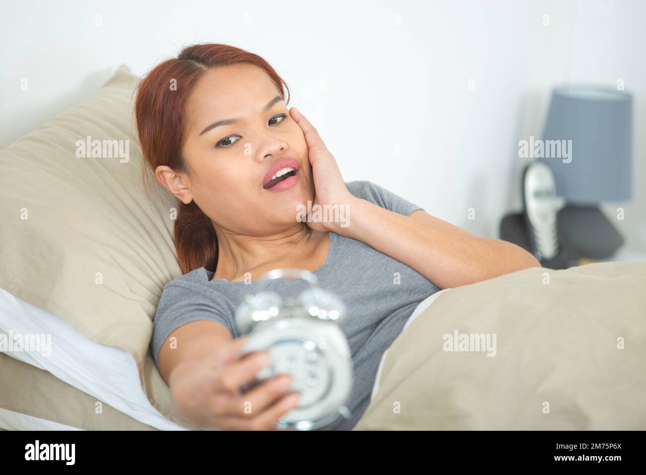 shocked young woman waking up with alarm Stock Photo - Alamy