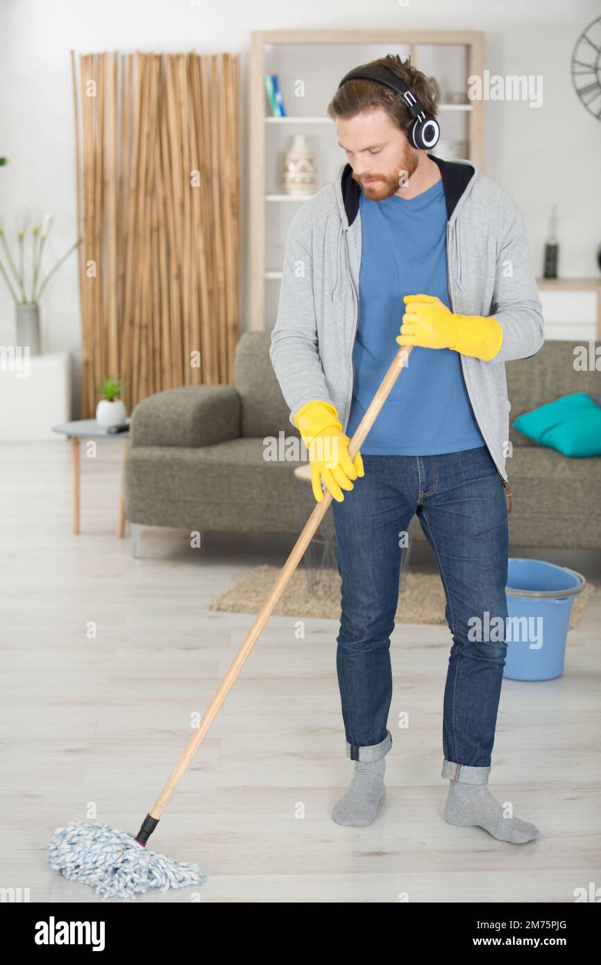 handsome concentrated man in yellow rubber gloves cleaning his flat ...