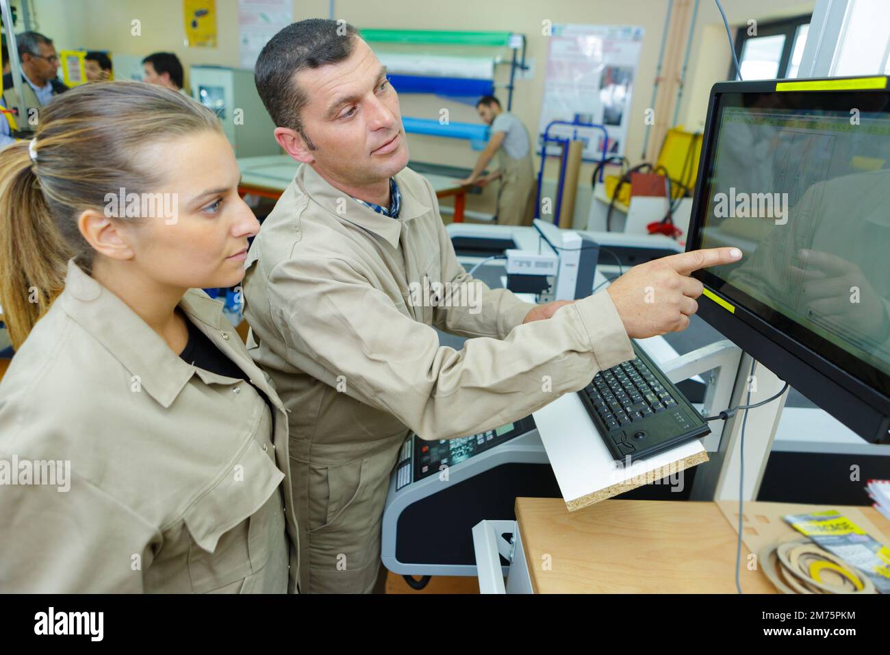 techncian and apprentice looking at computer monitor during training ...