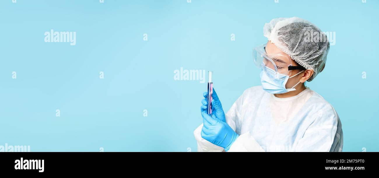 Lab worker mixing chemicals in sample test tube, wearing personal ...