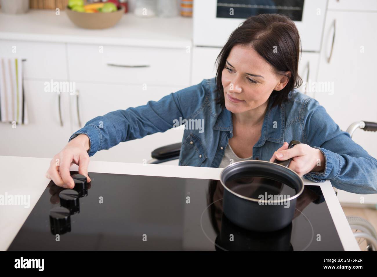 disabled woman in a wheelchair cooking on the hob Stock Photo - Alamy