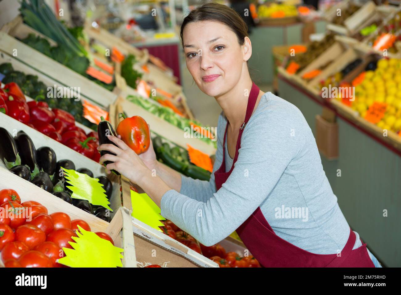 portrait of adult female selling fruits and vegetables in store Stock ...