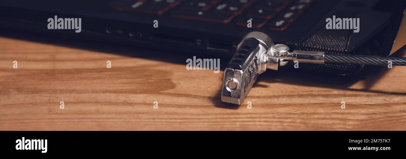 The black laptop is locked with a cable lock. Panorama of laptop ...
