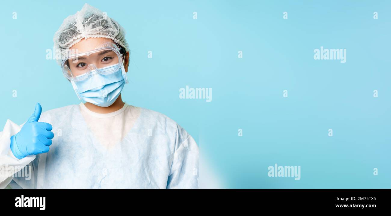 Smiling asian female nurse or doctor, wearing ppe, personal protective ...