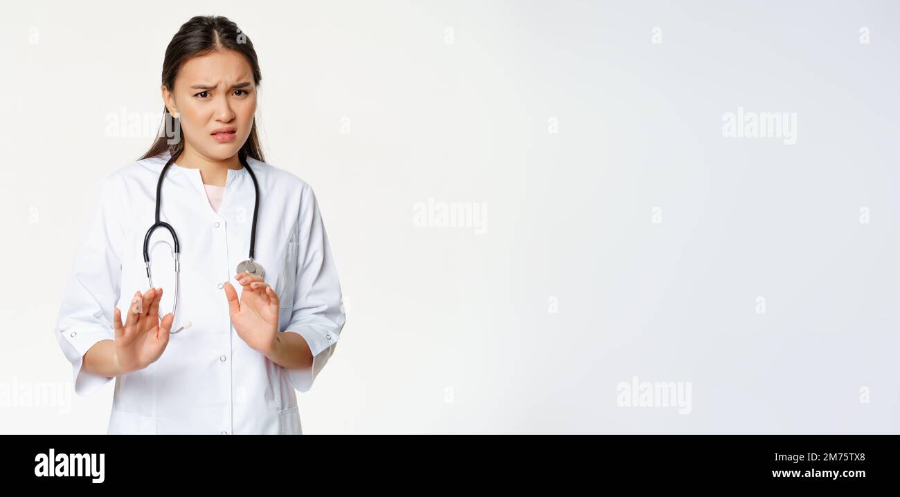 Disgusted asian female doctor rejecting, saying no, looking with ...