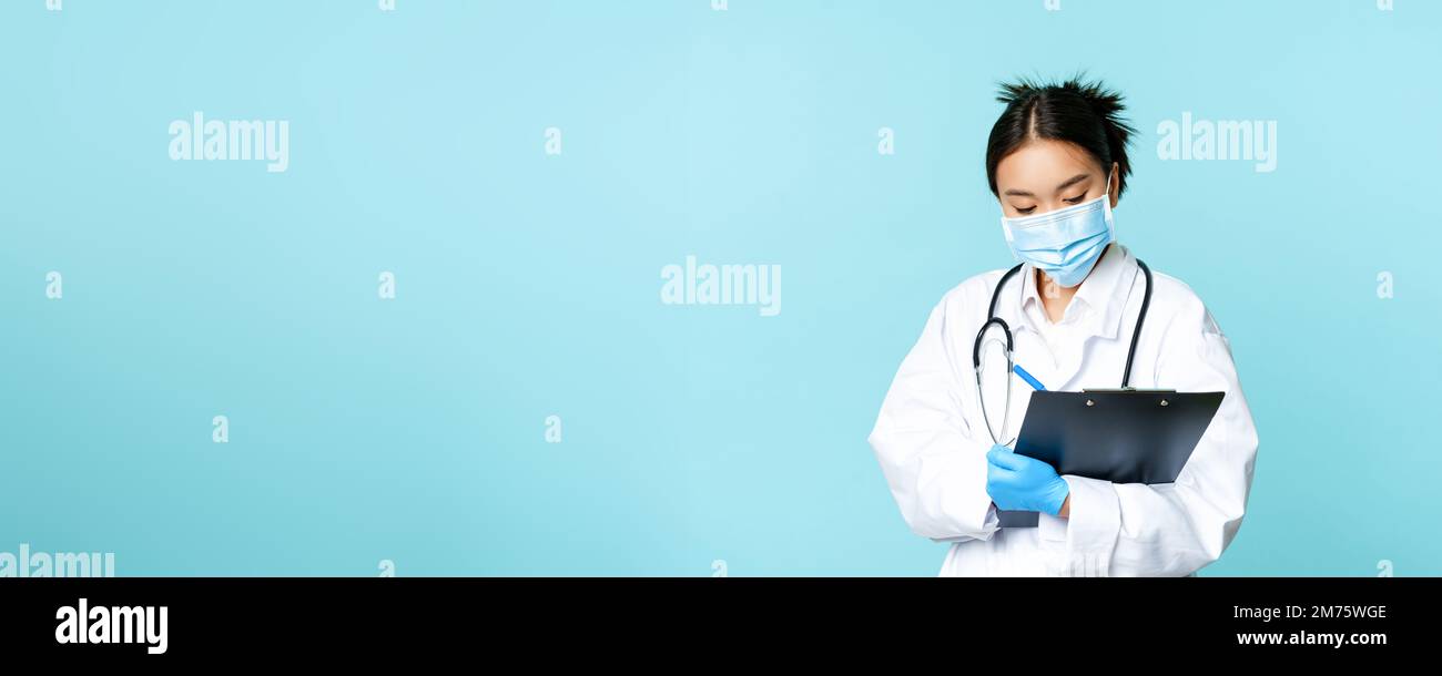 Image of korean doctor, female nurse in medical face mask, writing down ...