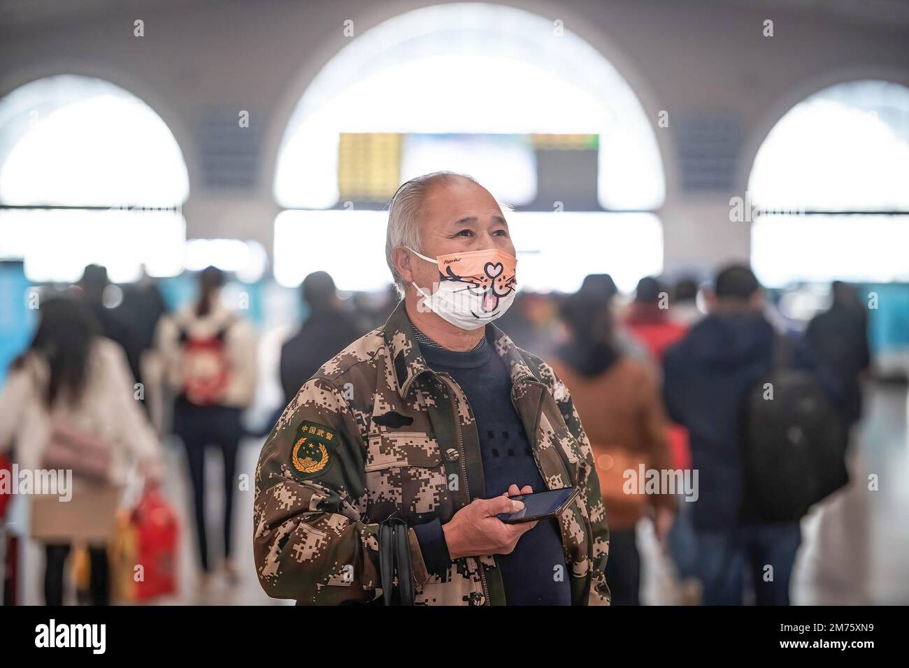 A passenger wearing face mask looks at a train timetable on a big ...