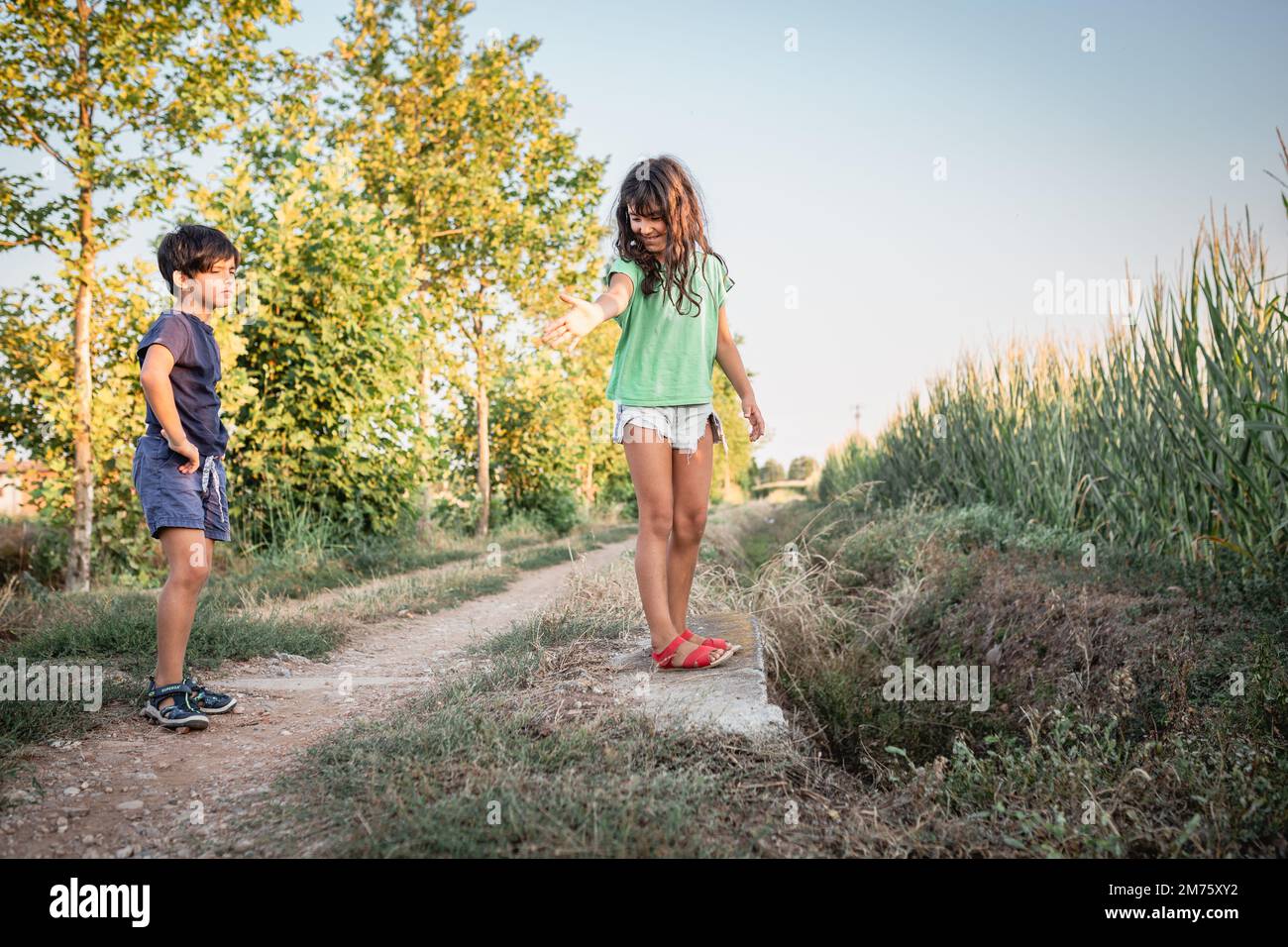 side view of two girls wearing shorts playing together in corn field ...