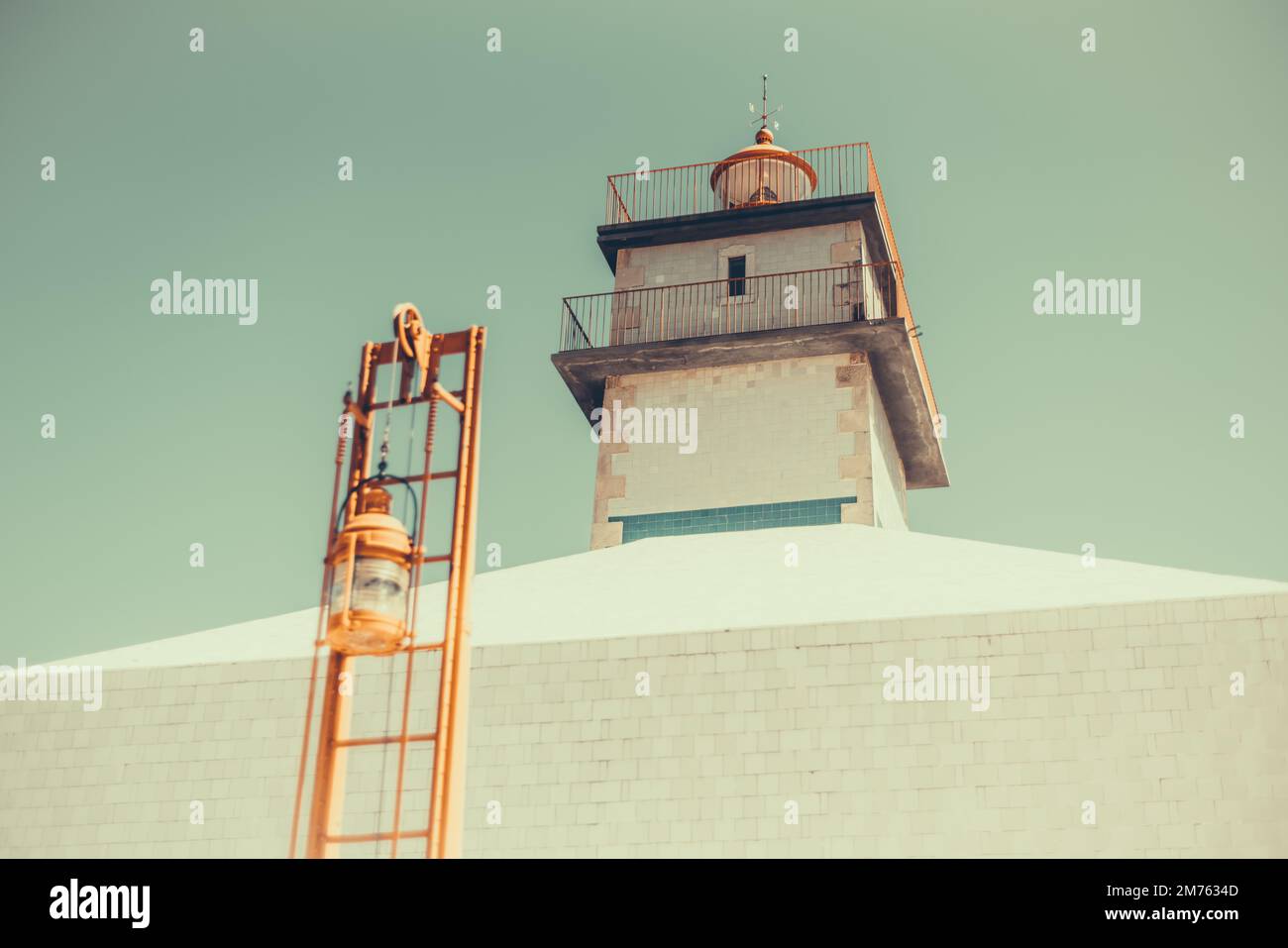 A wide low-angle shot of an old white-colored lighthouse with a ...