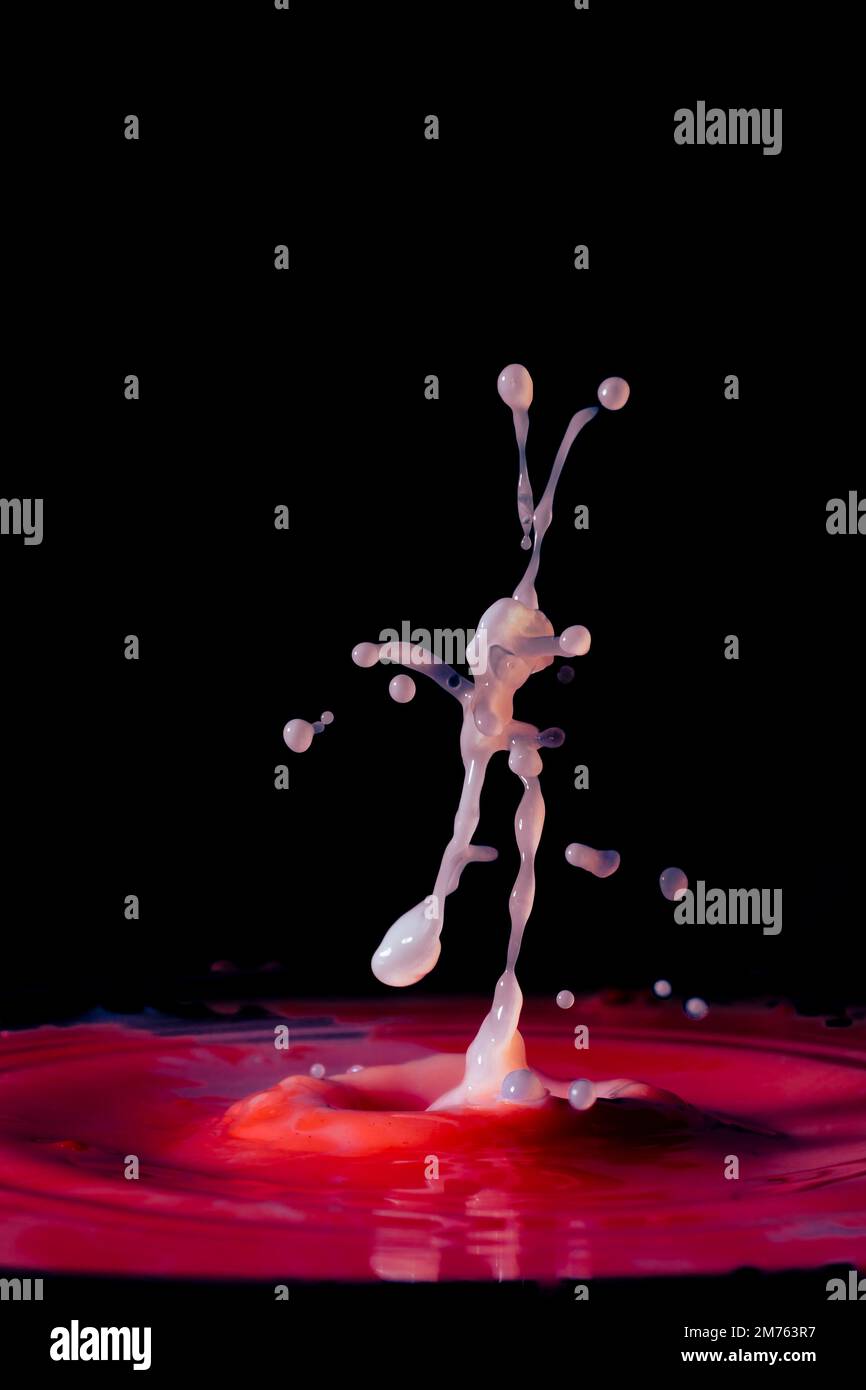 falling white water drops formed a figure when falling colliding on red ...