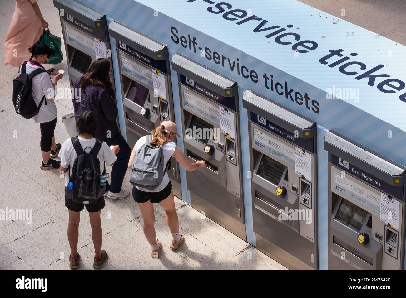 People buying tickets from self-service tickets machines inside ...