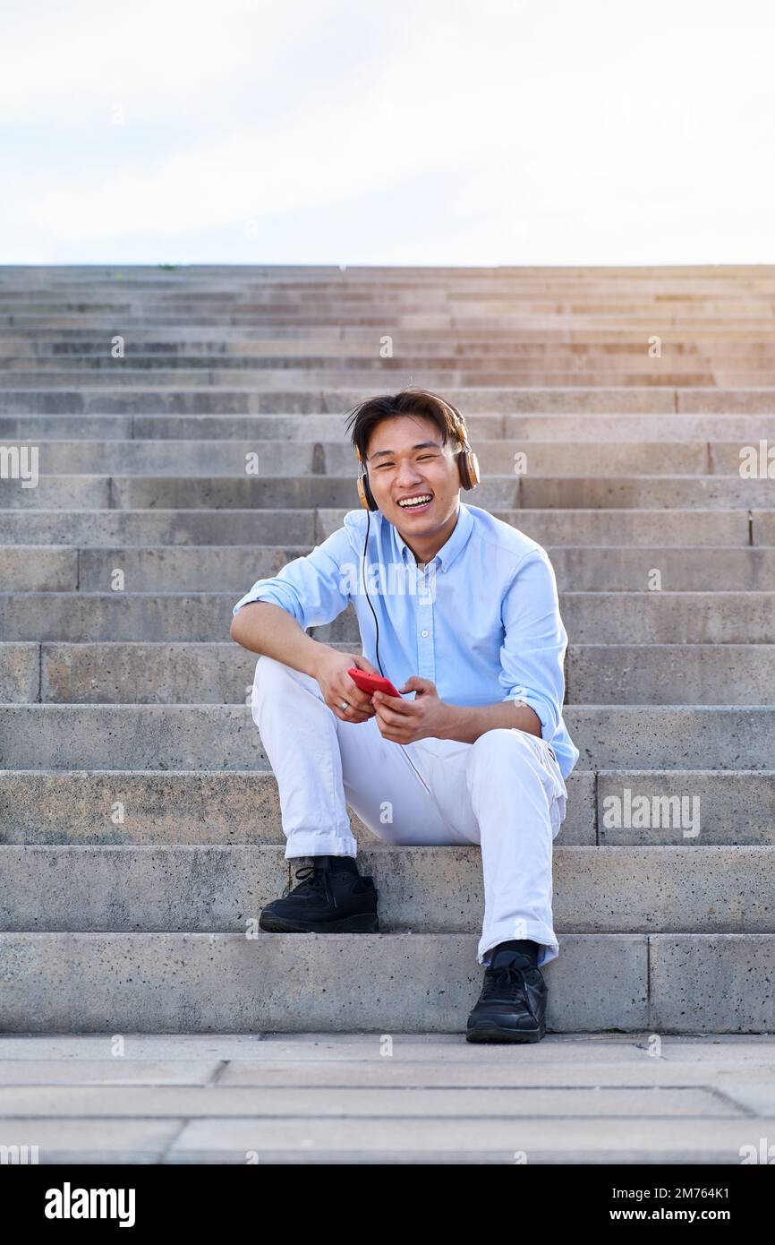 Happy portrait of a boy using headphones to listen music sitting on ...