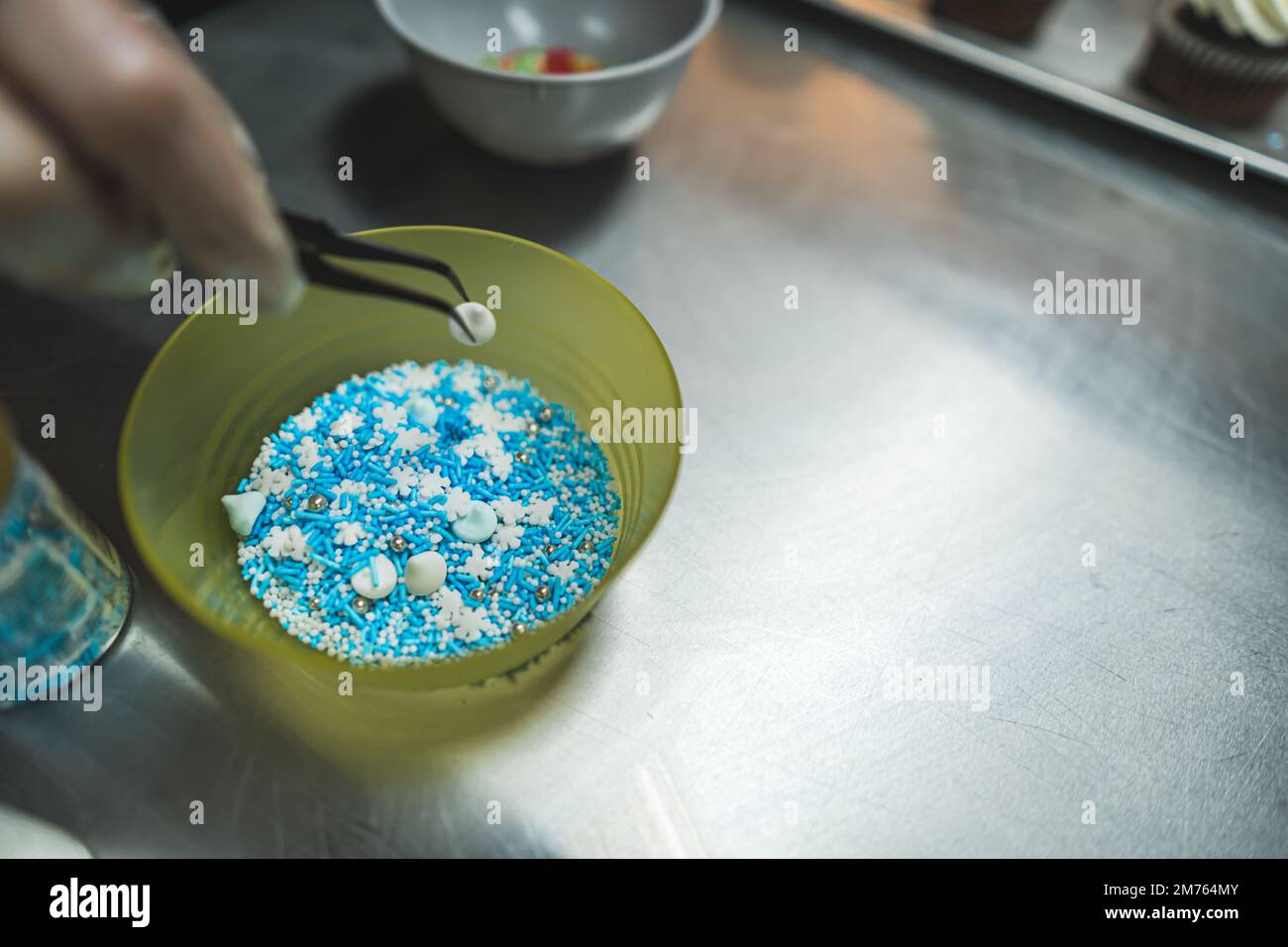 Professional baker using tweezers to decorate pastries. Cupcake ...