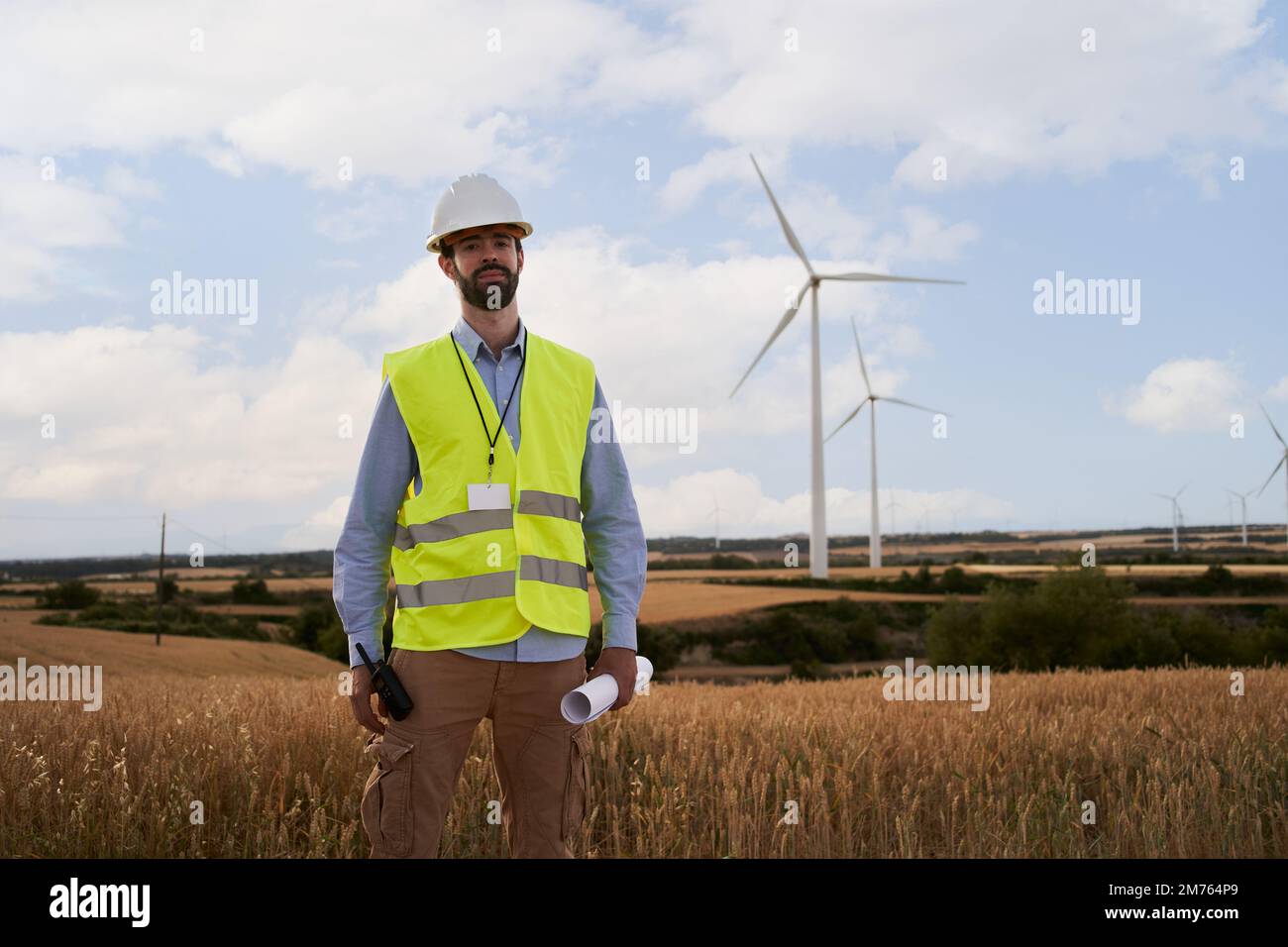 Working technical engineer looking at camera standing in a wind farm ...