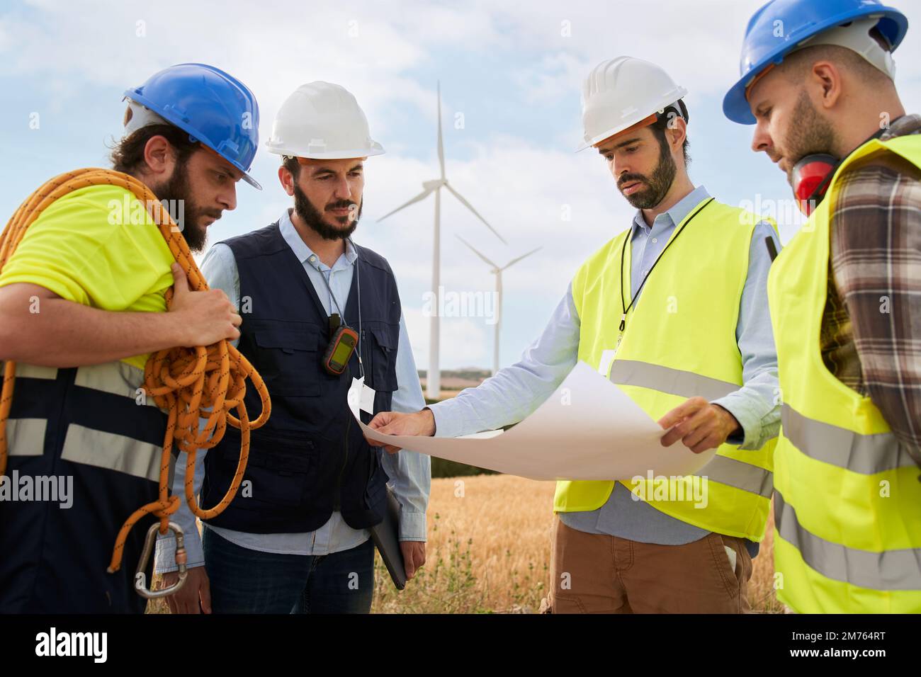 Group of engineers talking and working with a blueprint in an ...